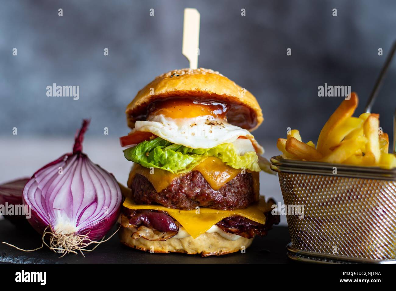 Homemade cheeseburger placed on wooden desk, with the onion and french ...