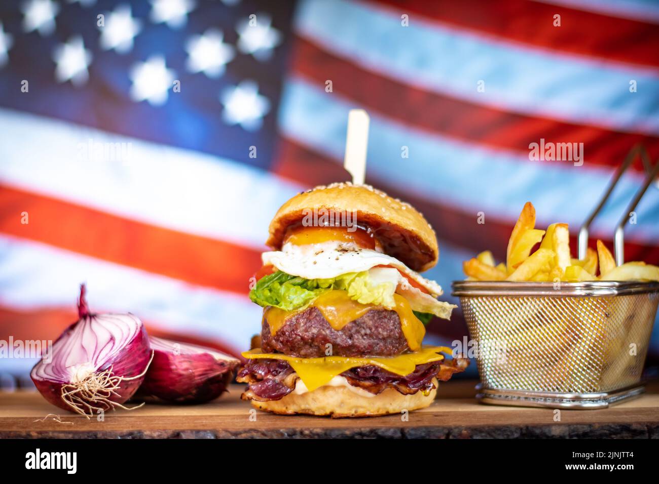 Cheeseburger with french fries and onion is placed on wooden desk ...
