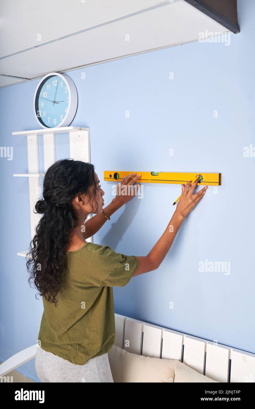 Young woman using construction level to measure the wall Stock Photo ...