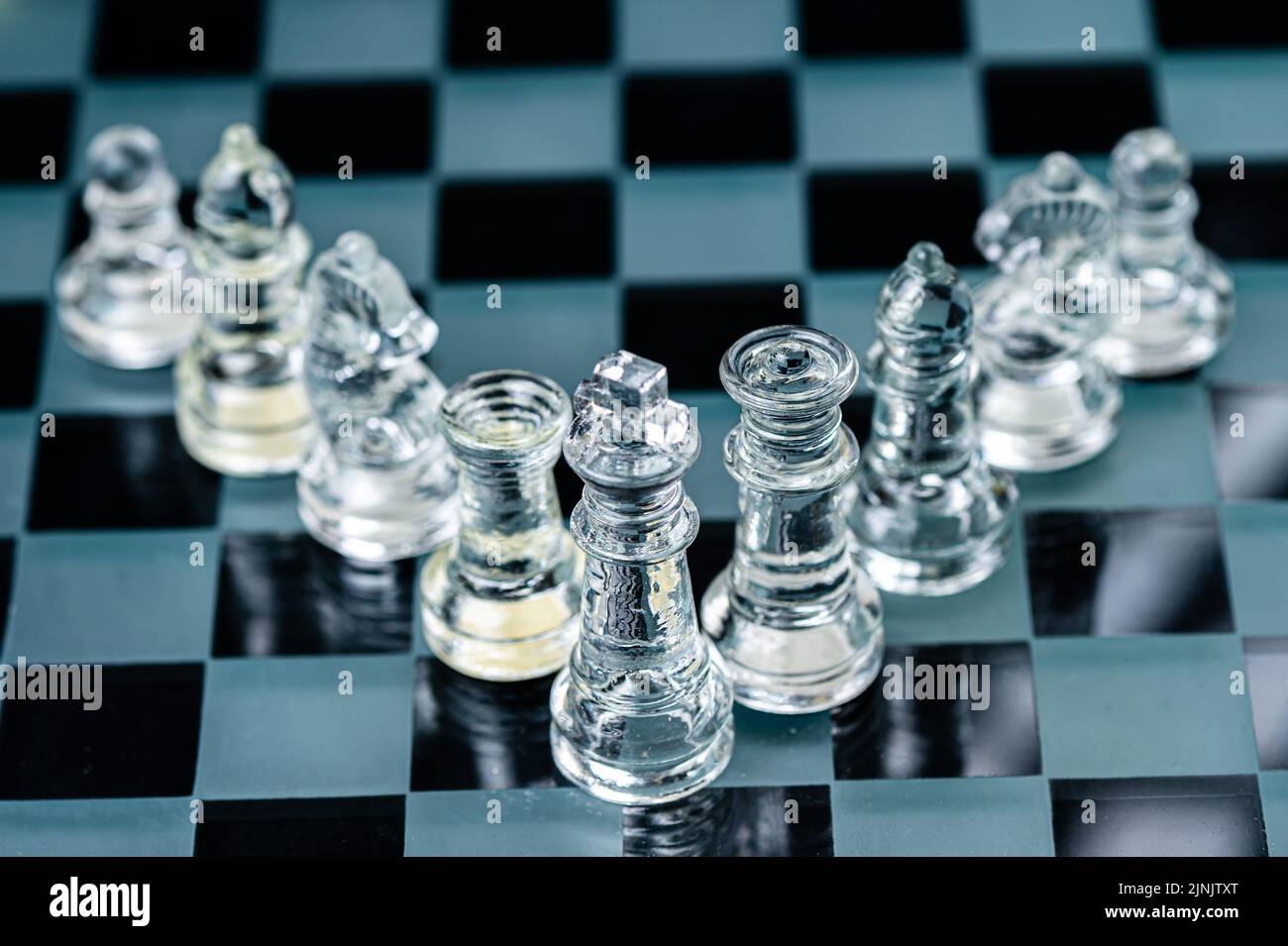 clear glass chess figures arranged in a row reflecting in glass ...