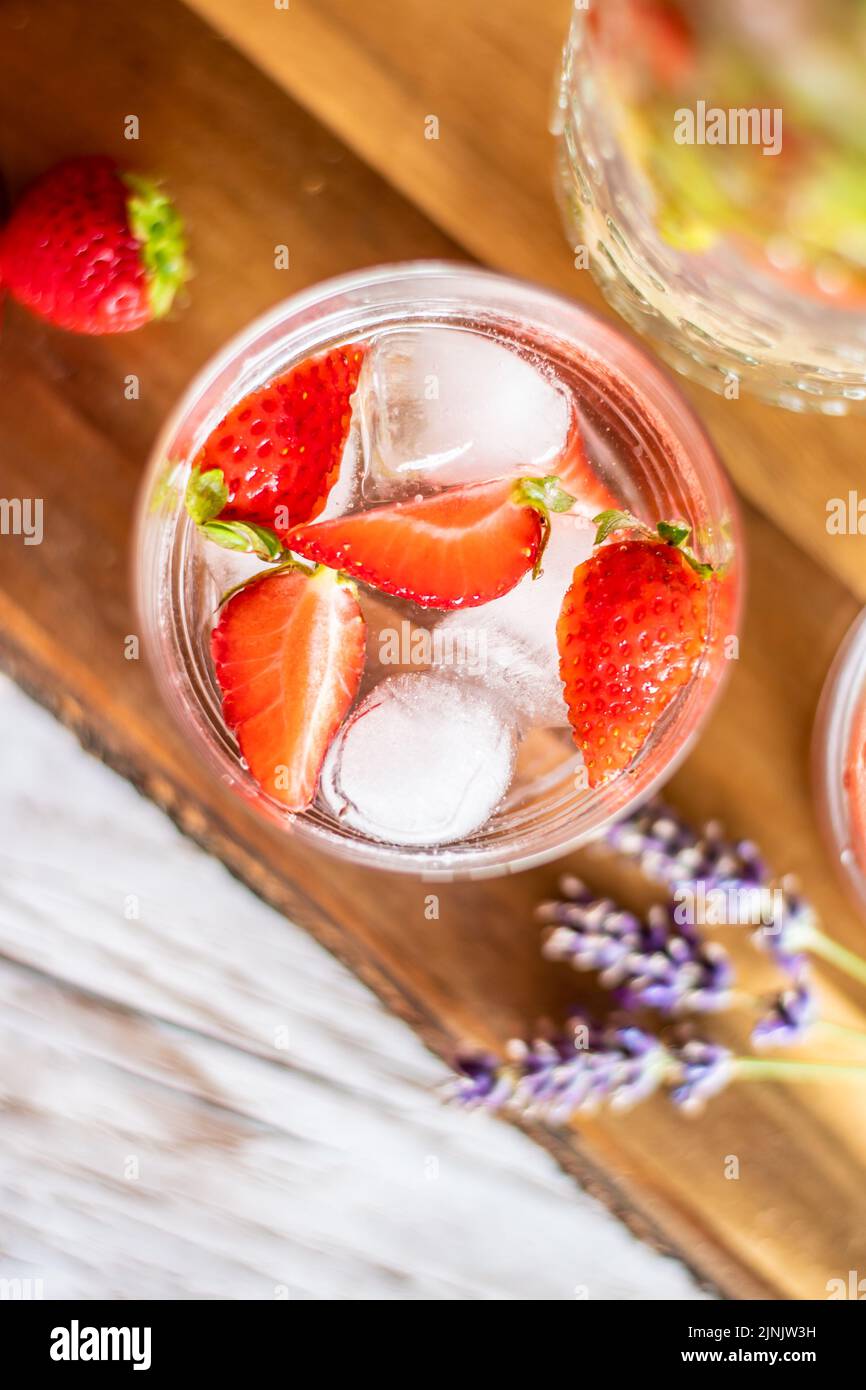 Fresh fruit summer drink with strawberry, lime and ice placed on wooden ...