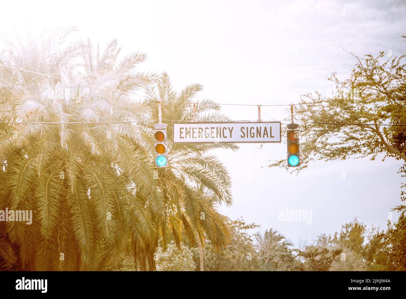 An emergency signal sign at green light up traffic lights hanging over ...