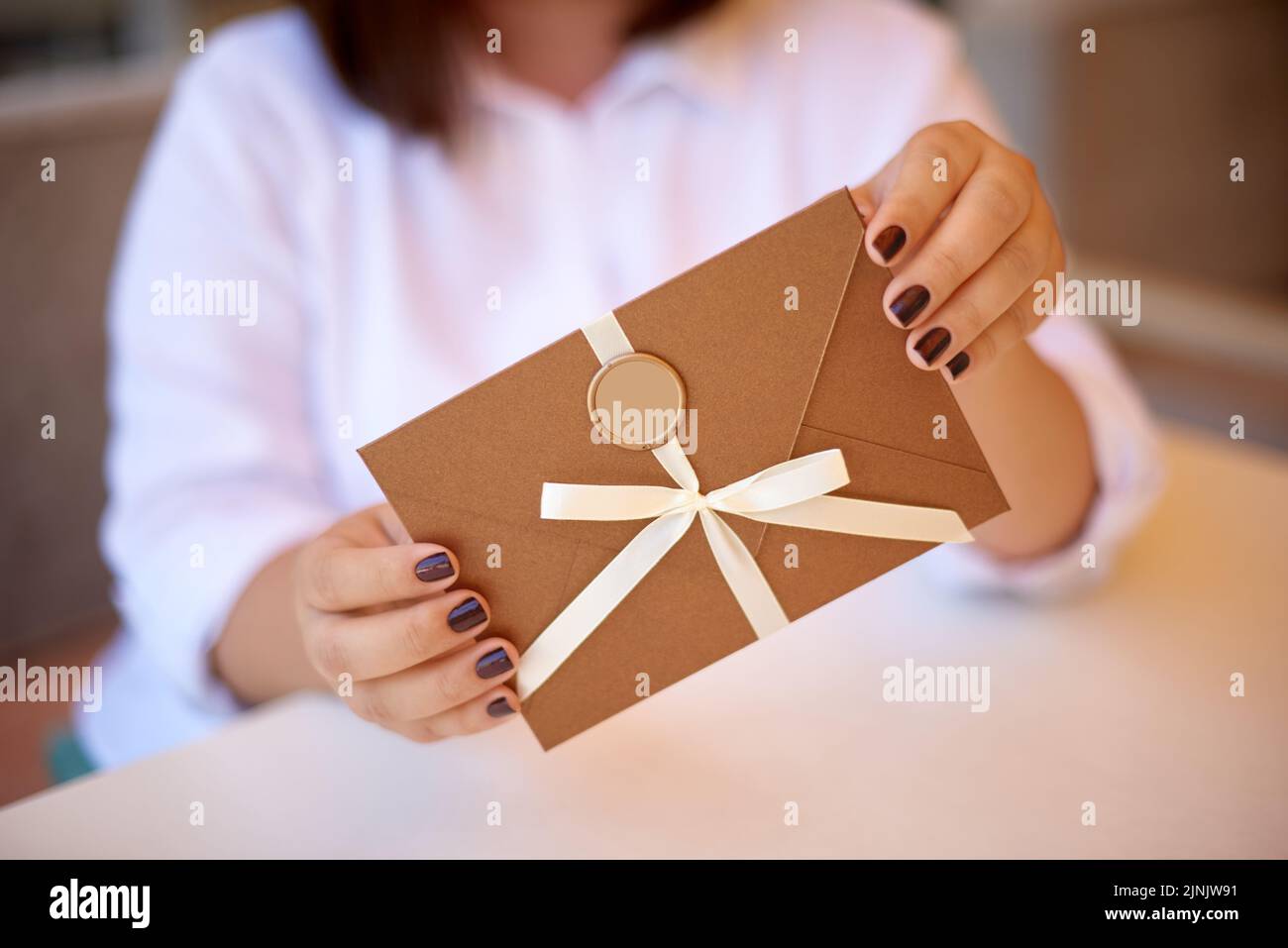 woman hands holding bronze invitation envelope with wax seal, gift ...