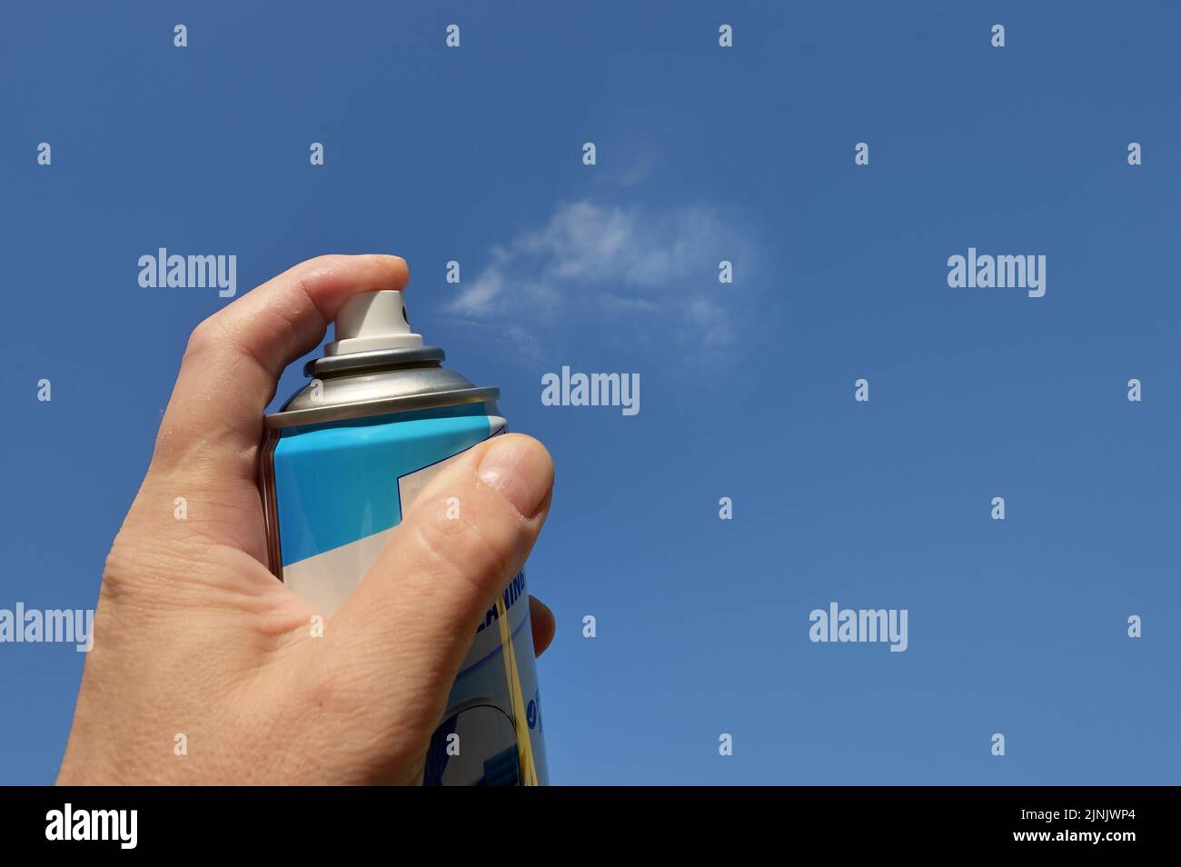 Abstract painting. Man painting with spray clouds on sky background ...
