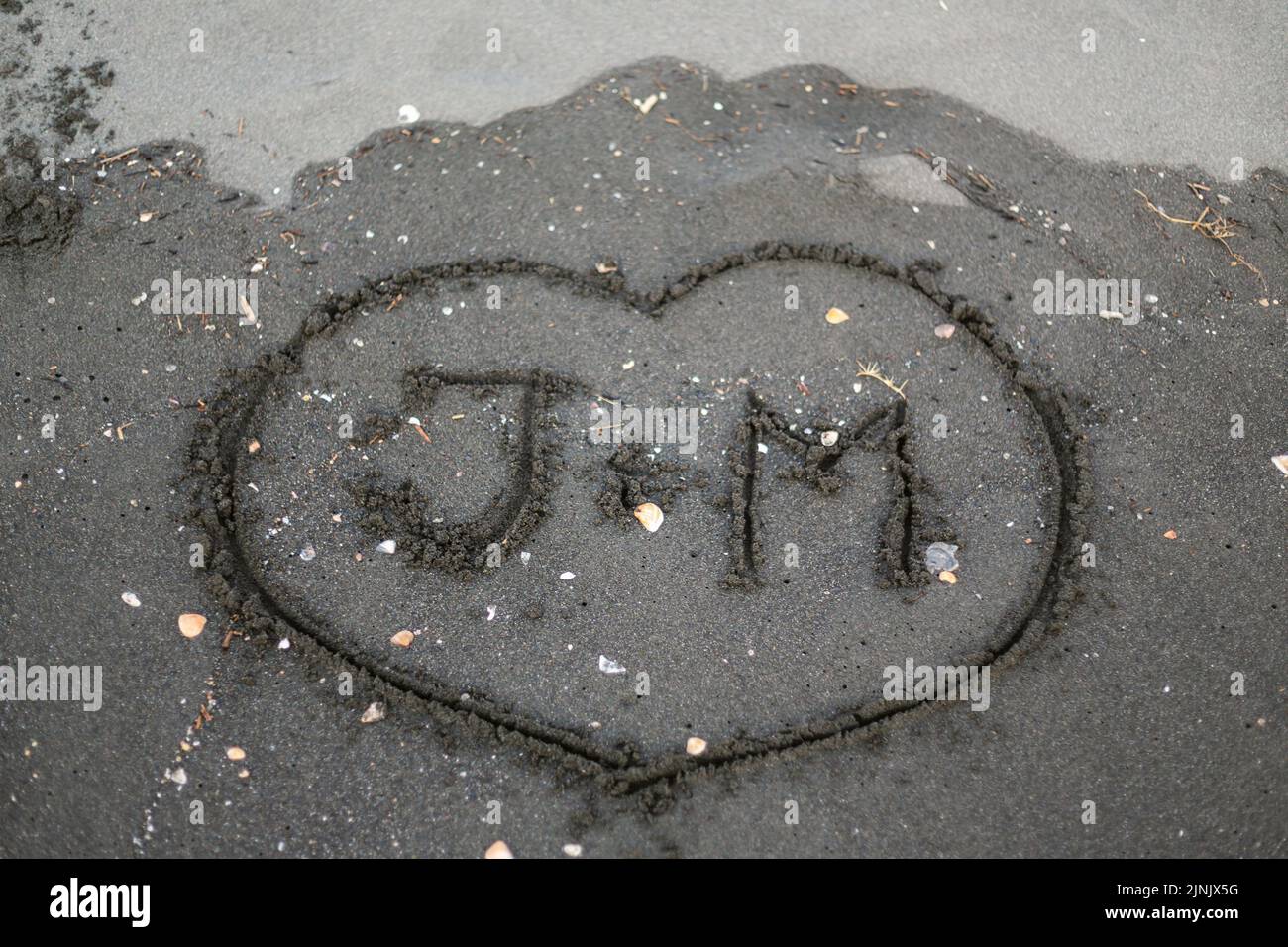 A sand with 'J plus M' symbol in heart shape Stock Photo - Alamy