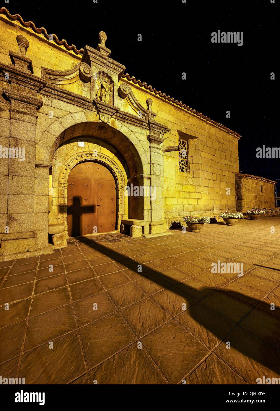 Romanesque church at night with the shadow of a cross on the facade ...