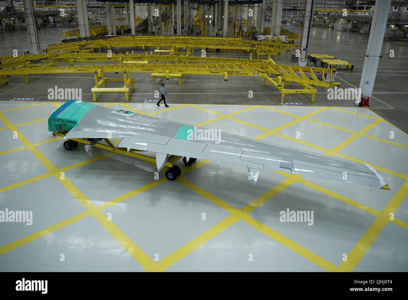 A member of staff walks past a plane wing at the division manufacturing ...