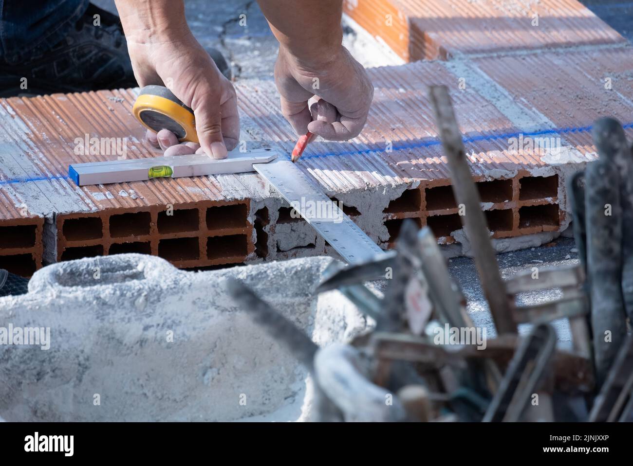 A bricklayer marks with a pencil the distance measured with a square on ...