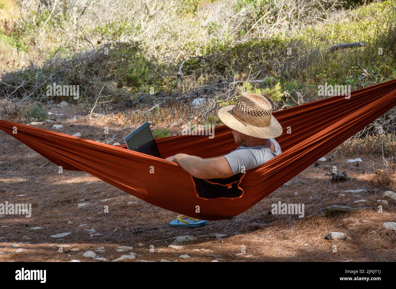 A view of a man relaxing in a hammock, using laptop computer Stock ...