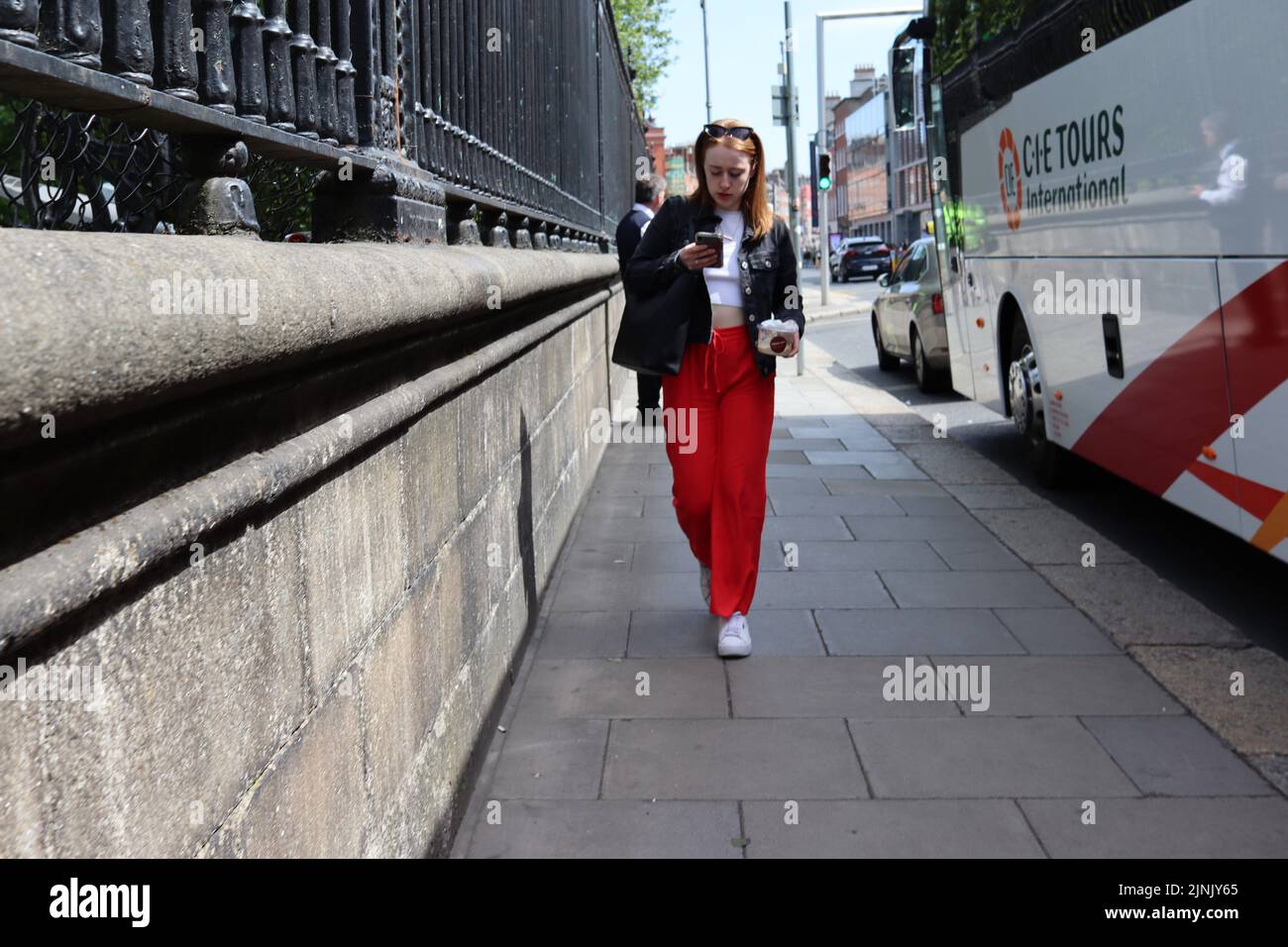 Woman texting while walking down the street next to the bus stop Stock ...