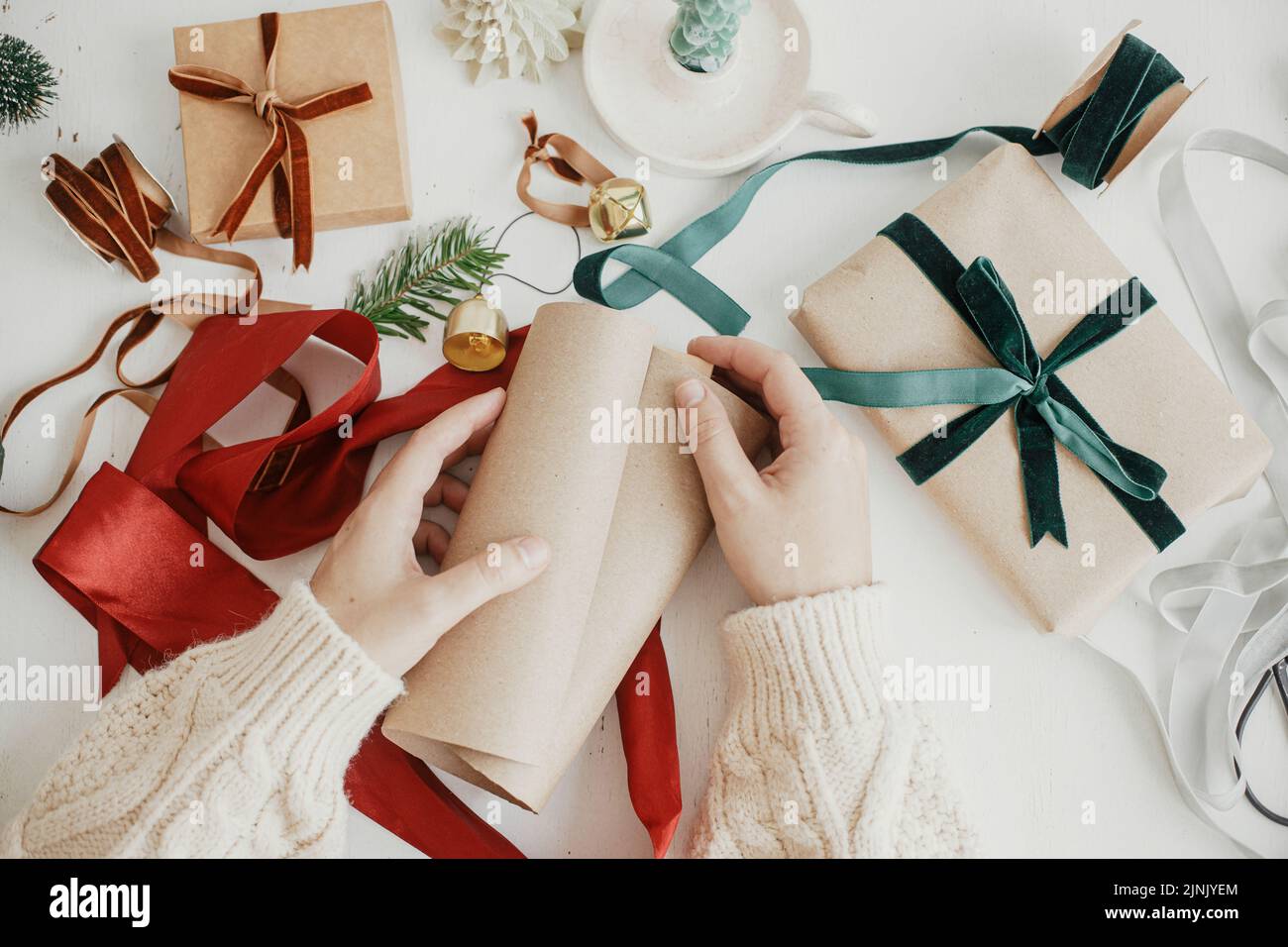 Hands wrapping stylish christmas gift flat lay. Person preparing simple ...
