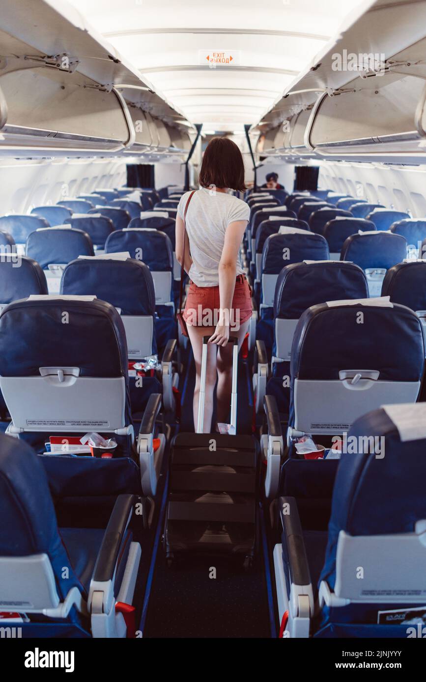Back view of young woman walking the aisle on plane Stock Photo - Alamy