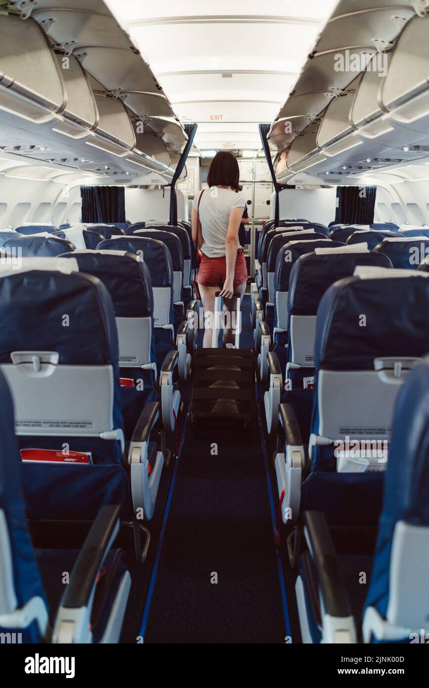 Back view of young woman walking the aisle on plane Stock Photo - Alamy