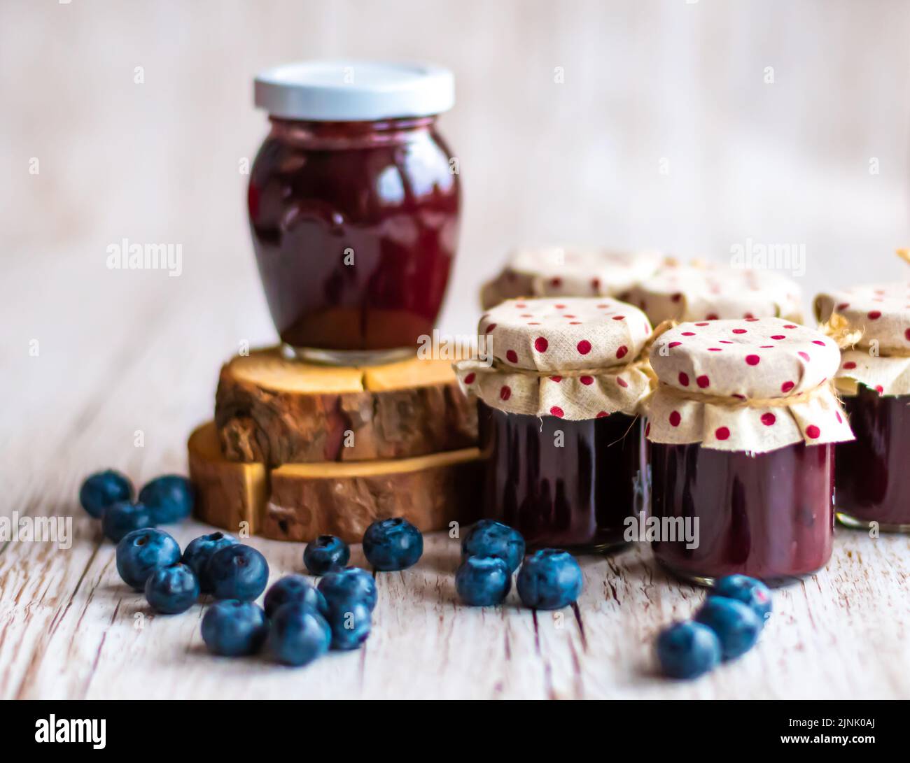 Blueberry jam placed in small glasses on wooden desk. Fresh blueberries ...