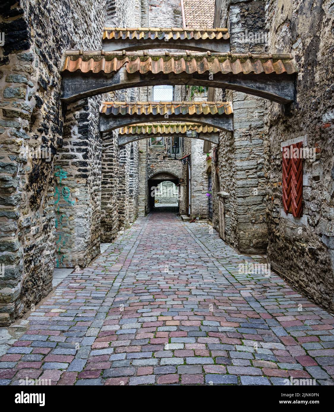 Narrow medieval alley with tile arches in the Estonian city of Tallinn ...