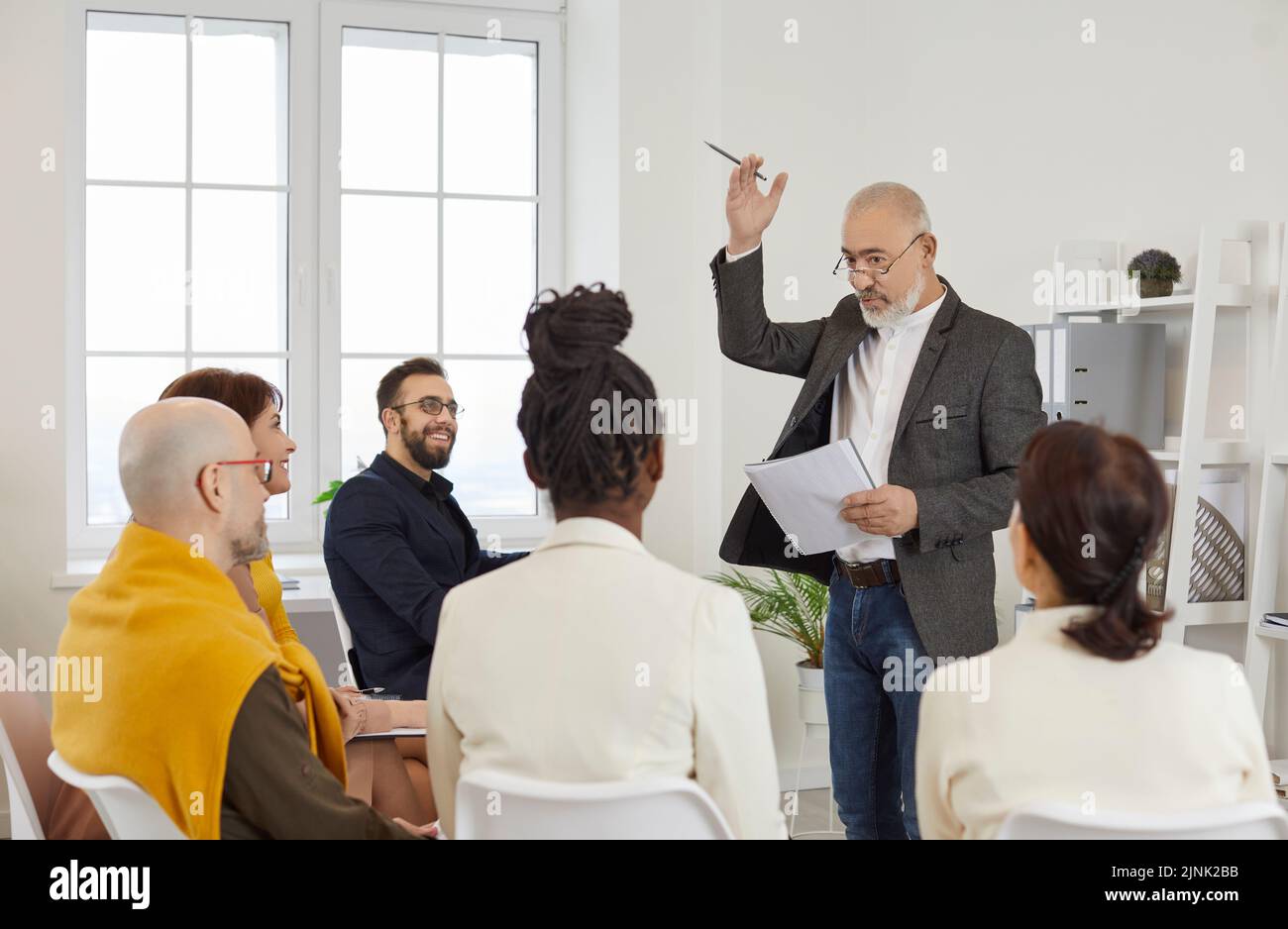 Professional coach or mentor talking to team of employees during ...