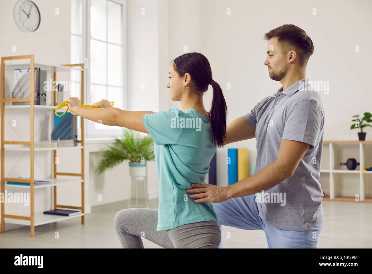 Young female patient with elastic band does stretching exercise with ...