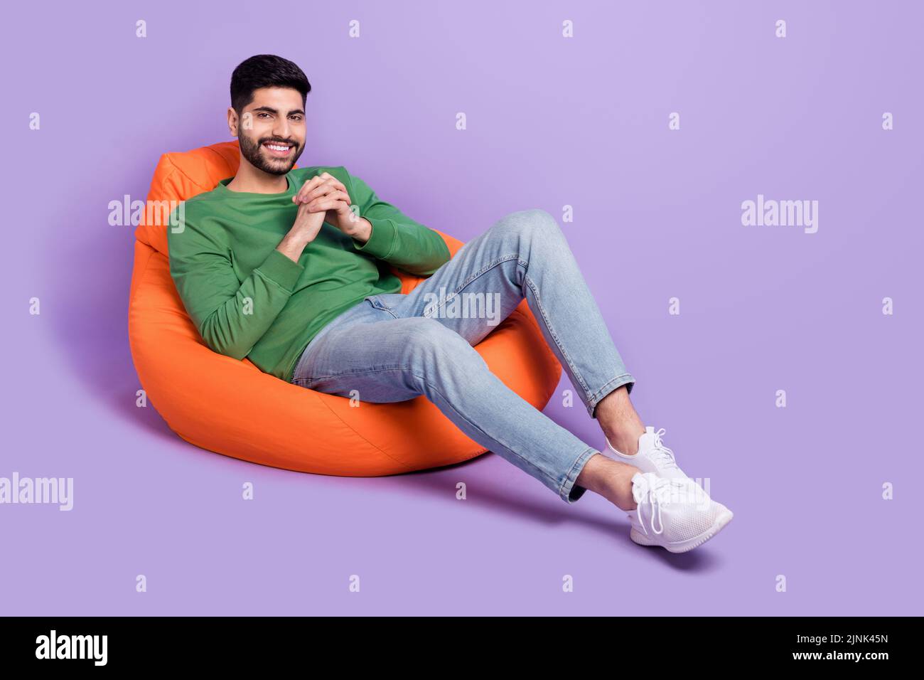 Full size photo of young latin man sit comfy beanbag hold hands toothy ...