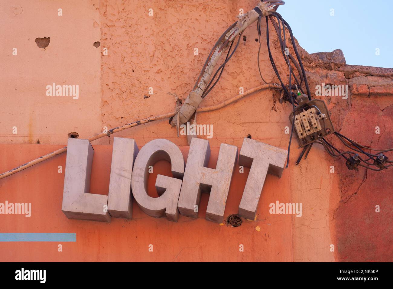 Old neon light letters spelling LIGHT and wires on orange wall at ...