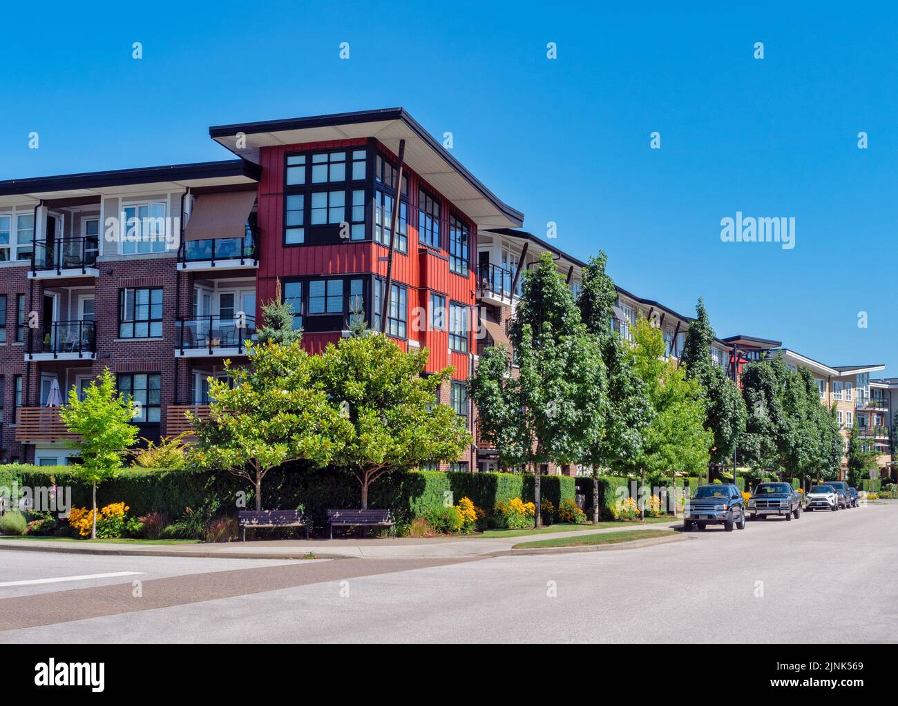 Red residential building on a street corner with cars parked beside ...