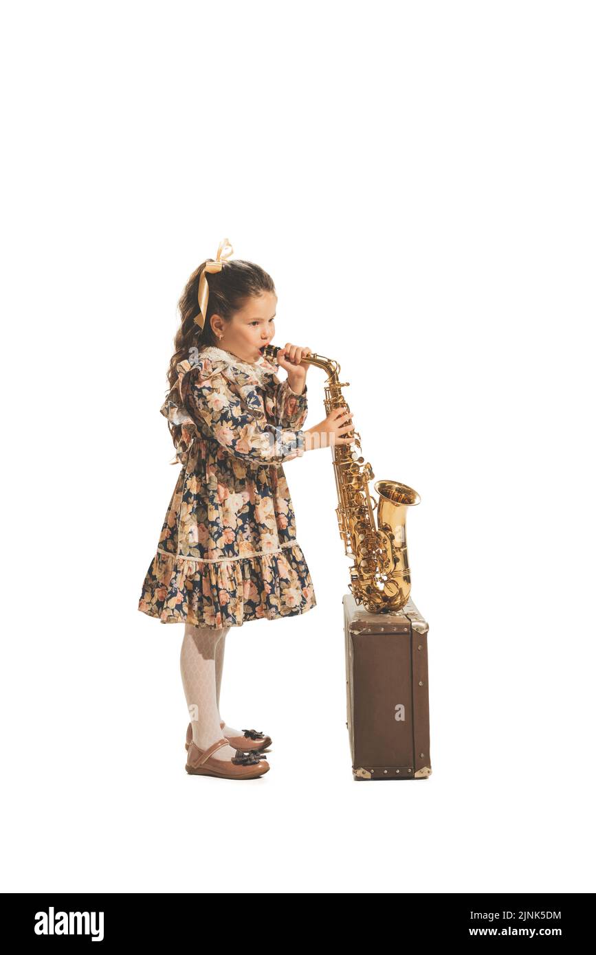 Charming little girl playing saxophone isolated on white studio ...