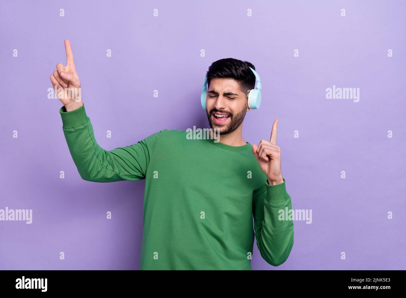 Photo of cheerful handsome good mood guy wear green pullover headphones ...