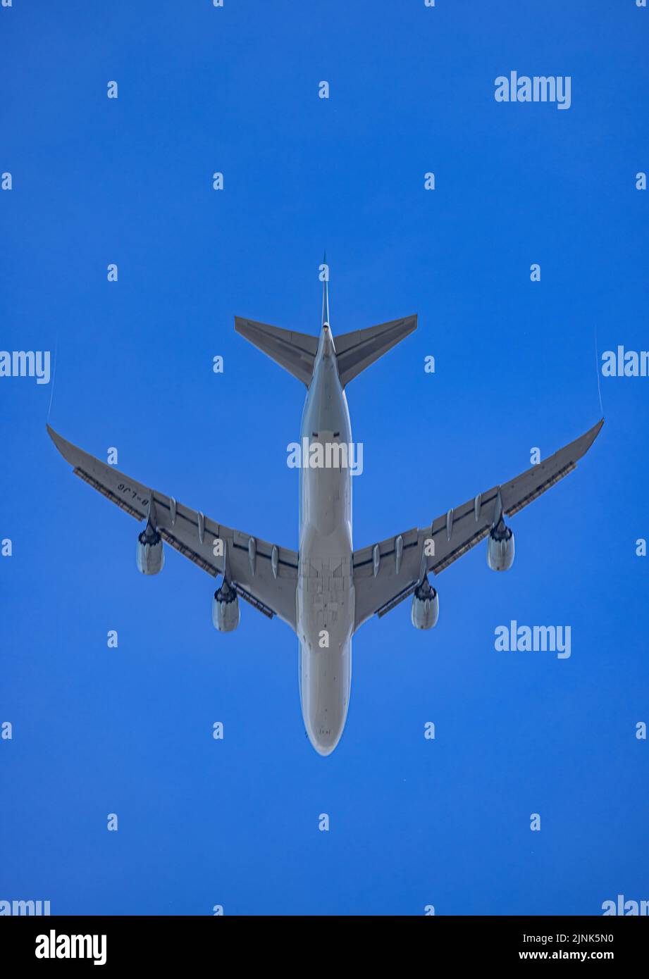 A vertical low angle of an airplane flying against a bright blue sky ...