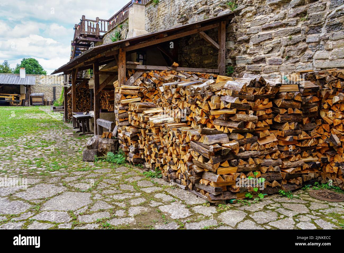 Firewood cut and stacked on the street in a medieval looking street ...