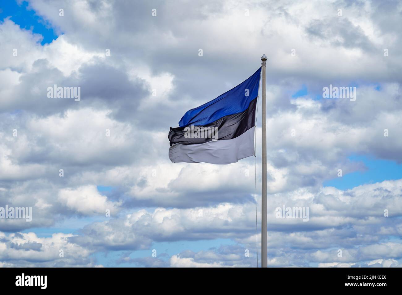 Flag of Estonia on the background of the blue sky and white clouds ...