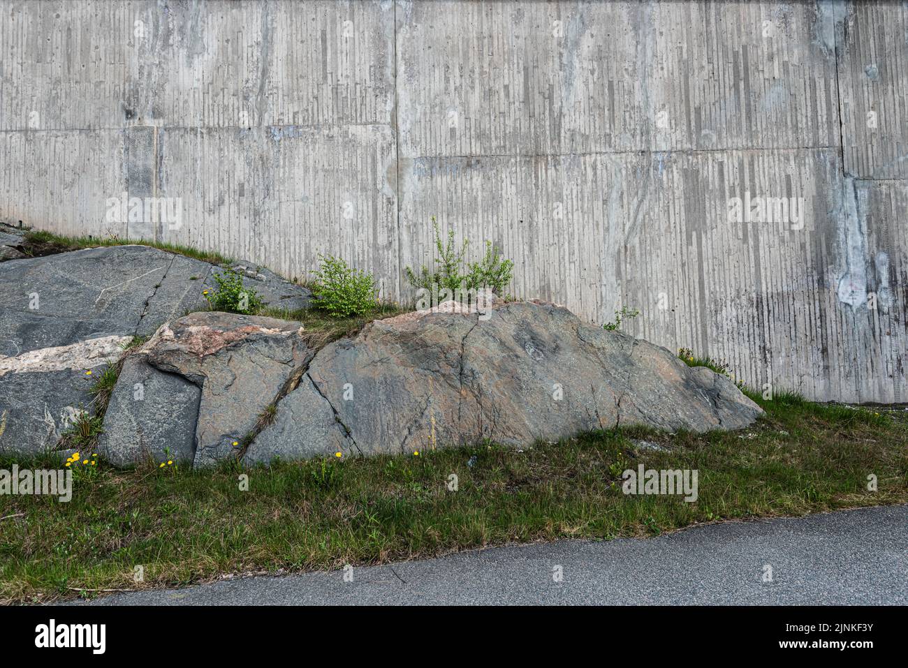 Grass, rockside and concrete by the side of a road Stock Photo - Alamy