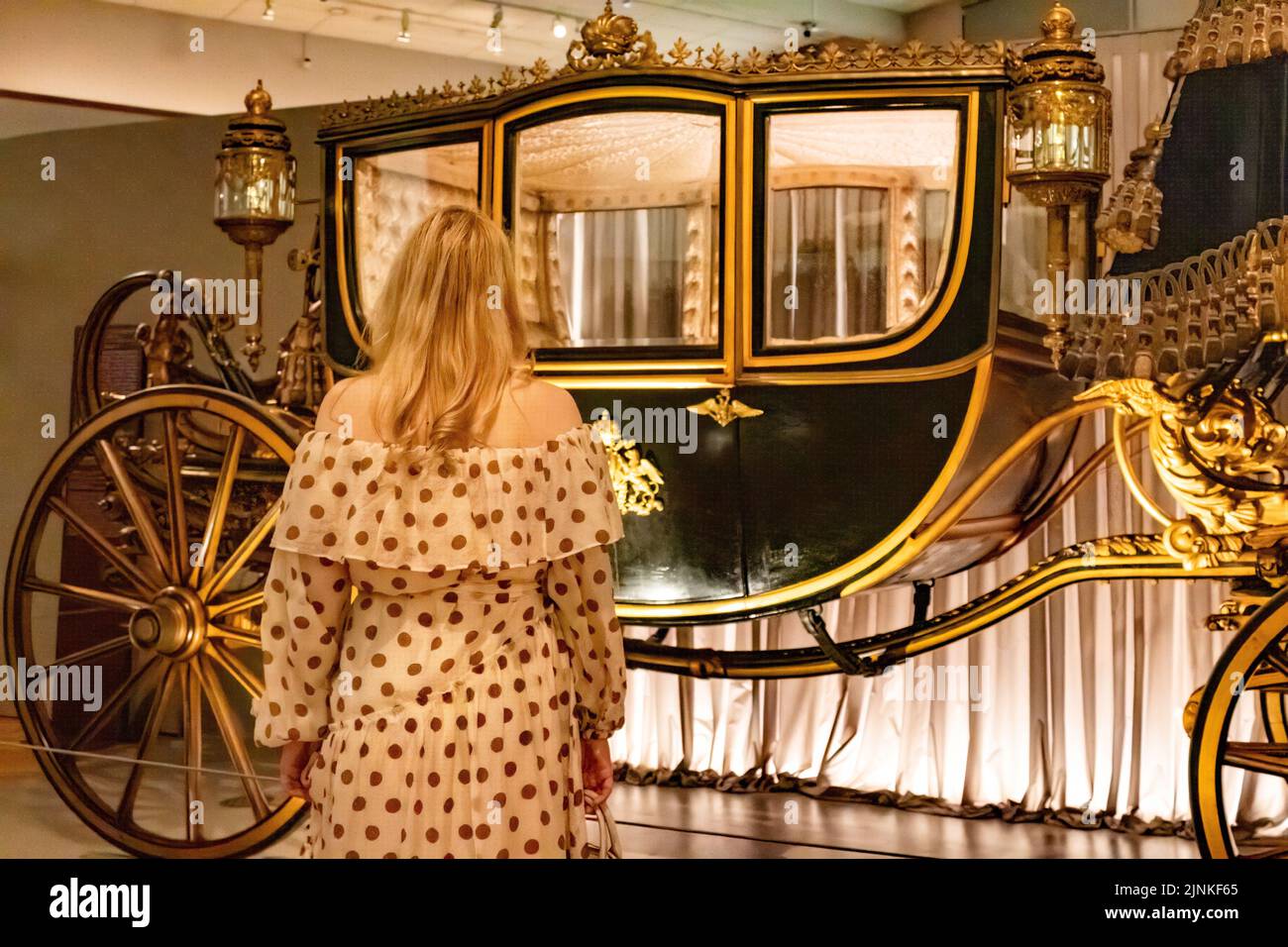 A back view of a female watching classical carriage in Carriage Museum ...