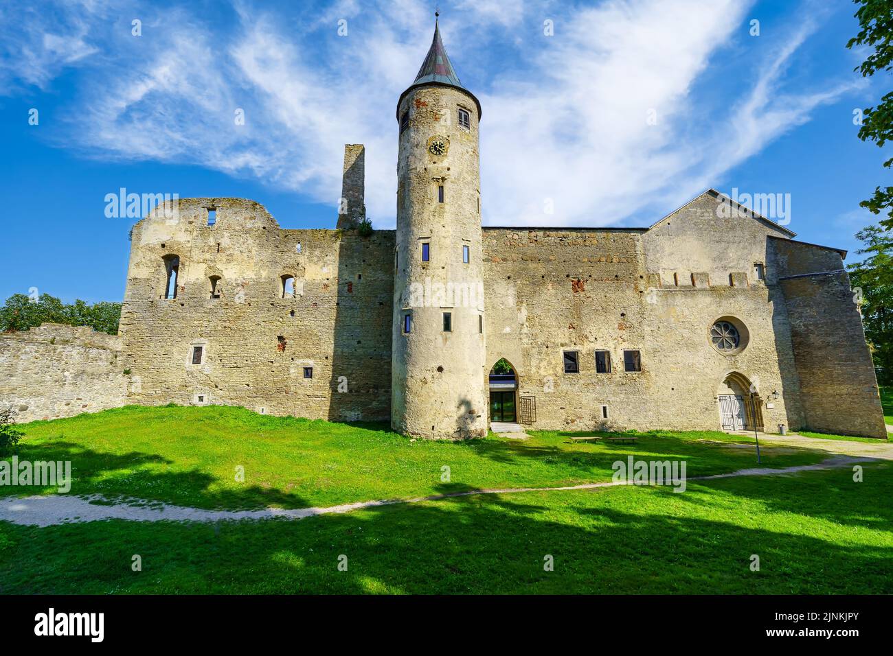 Medieval castle with high tower with clock and white clouds in sunny ...