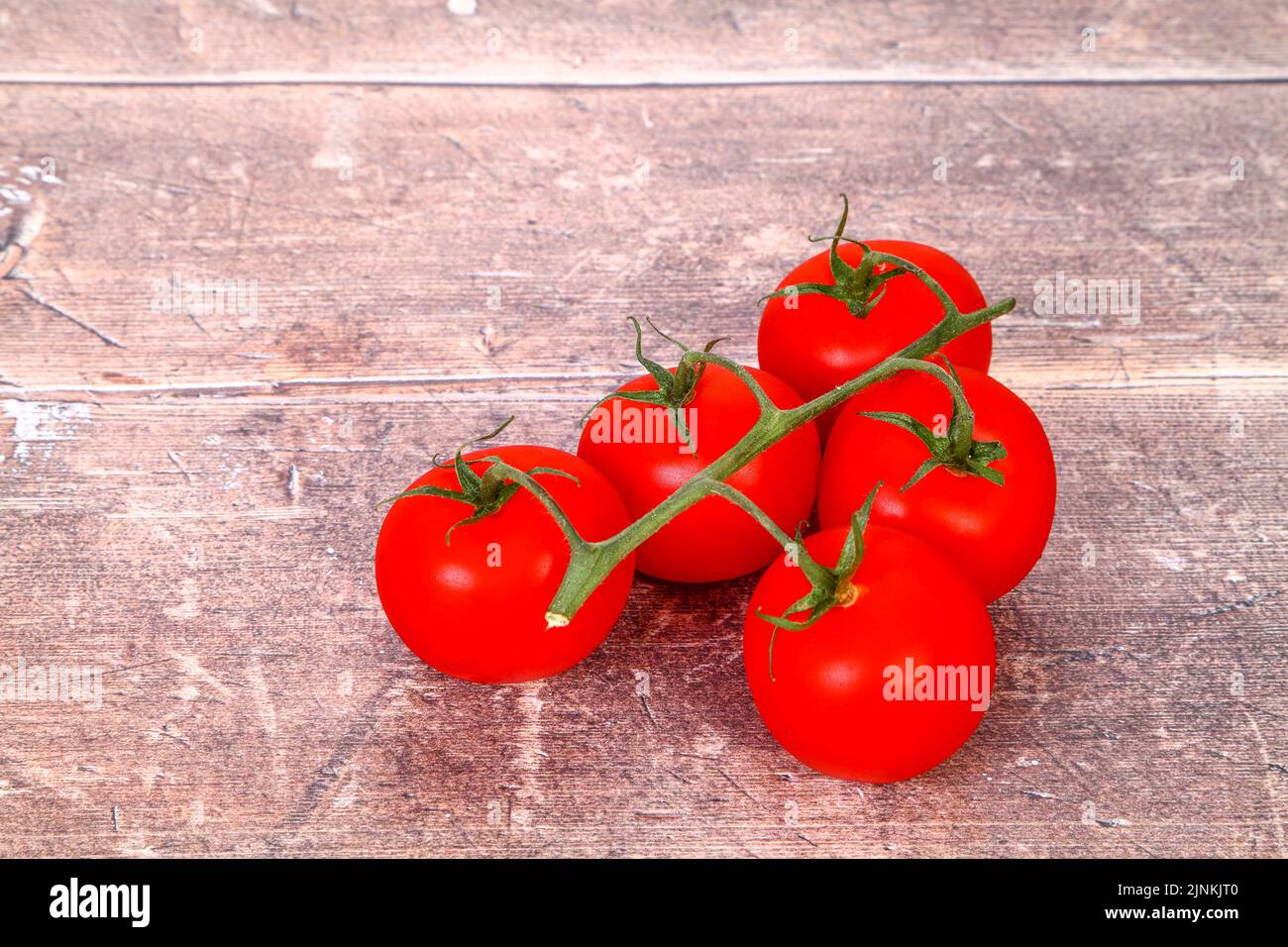 Ripe vine tomatoes isolated on a wooden table top Stock Photo - Alamy