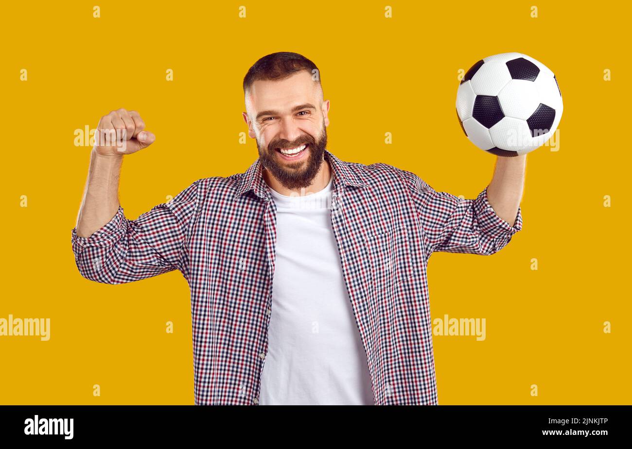 Happy man having fun at football match, holding ball, raising fist up ...