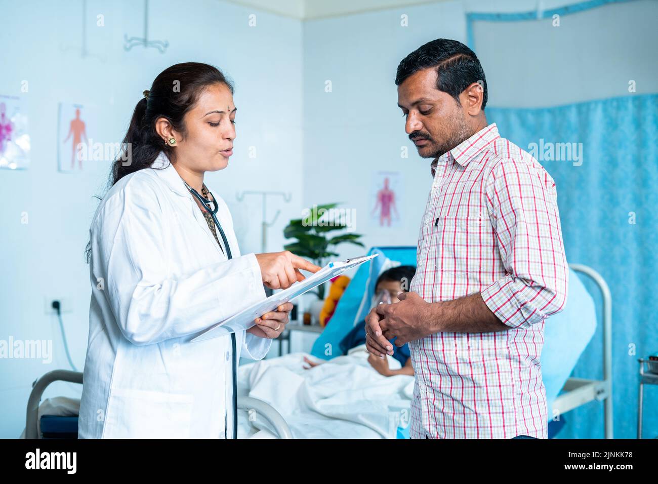 Doctor explaining patient health or medical report to worried father at ...