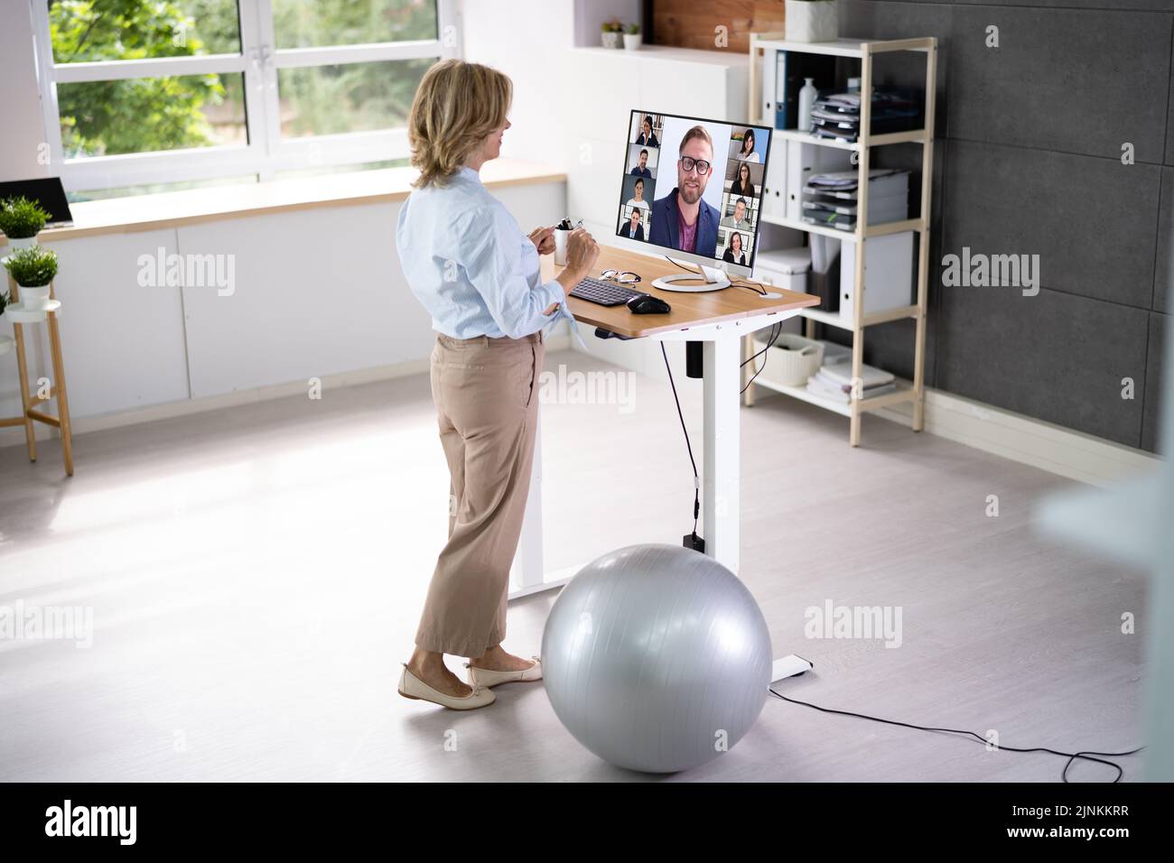 Woman Using Adjustable Height Standing Desk In Office For Good Posture ...