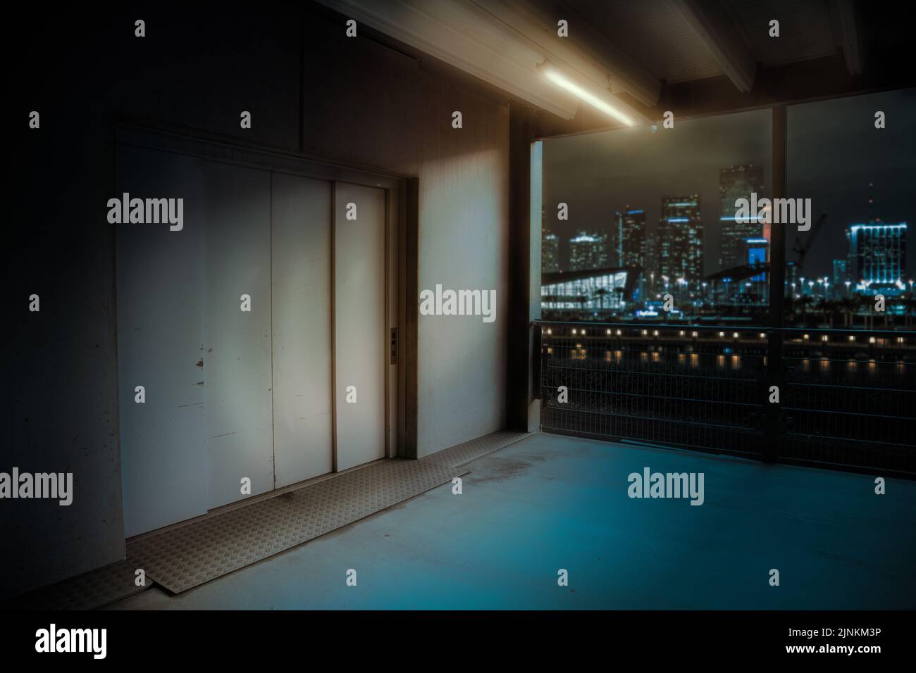 An elevator at a parking garage at night with a window overlooking the ...