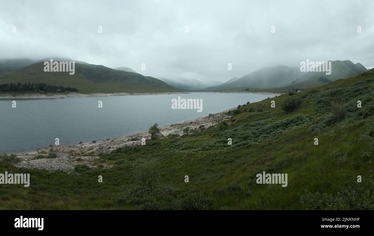Scottish landscape with lake surrounded by mountains and low clouds ...