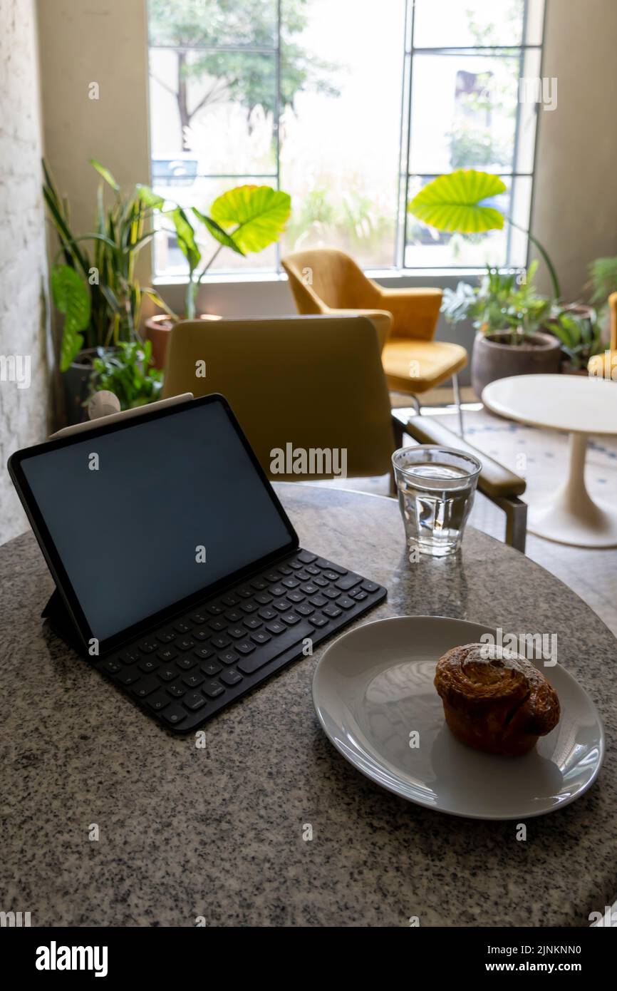 pancake or cupcake on ceramic plate, tablet in the back. Enjoying sweet ...