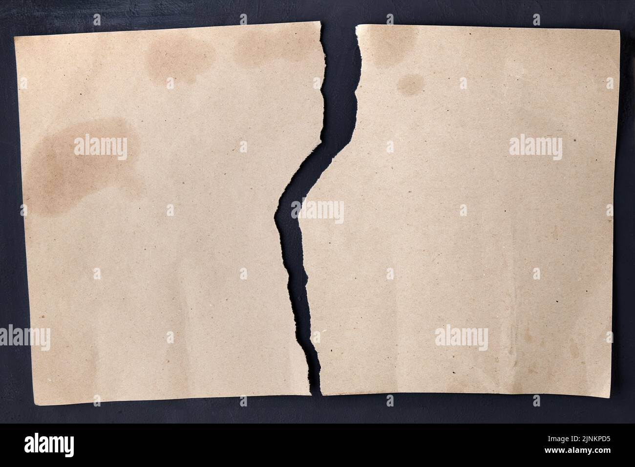 A sheet of brown craft paper torn into two halves. Crumpled oil-stained ...