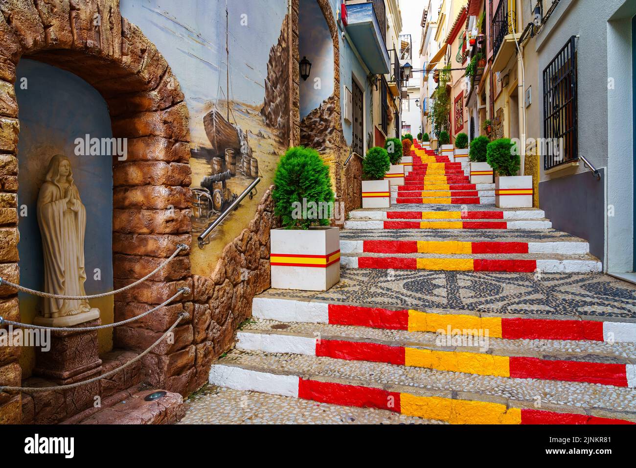 Narrow alley decorated with the flag of Spain on the steps. Calpe ...