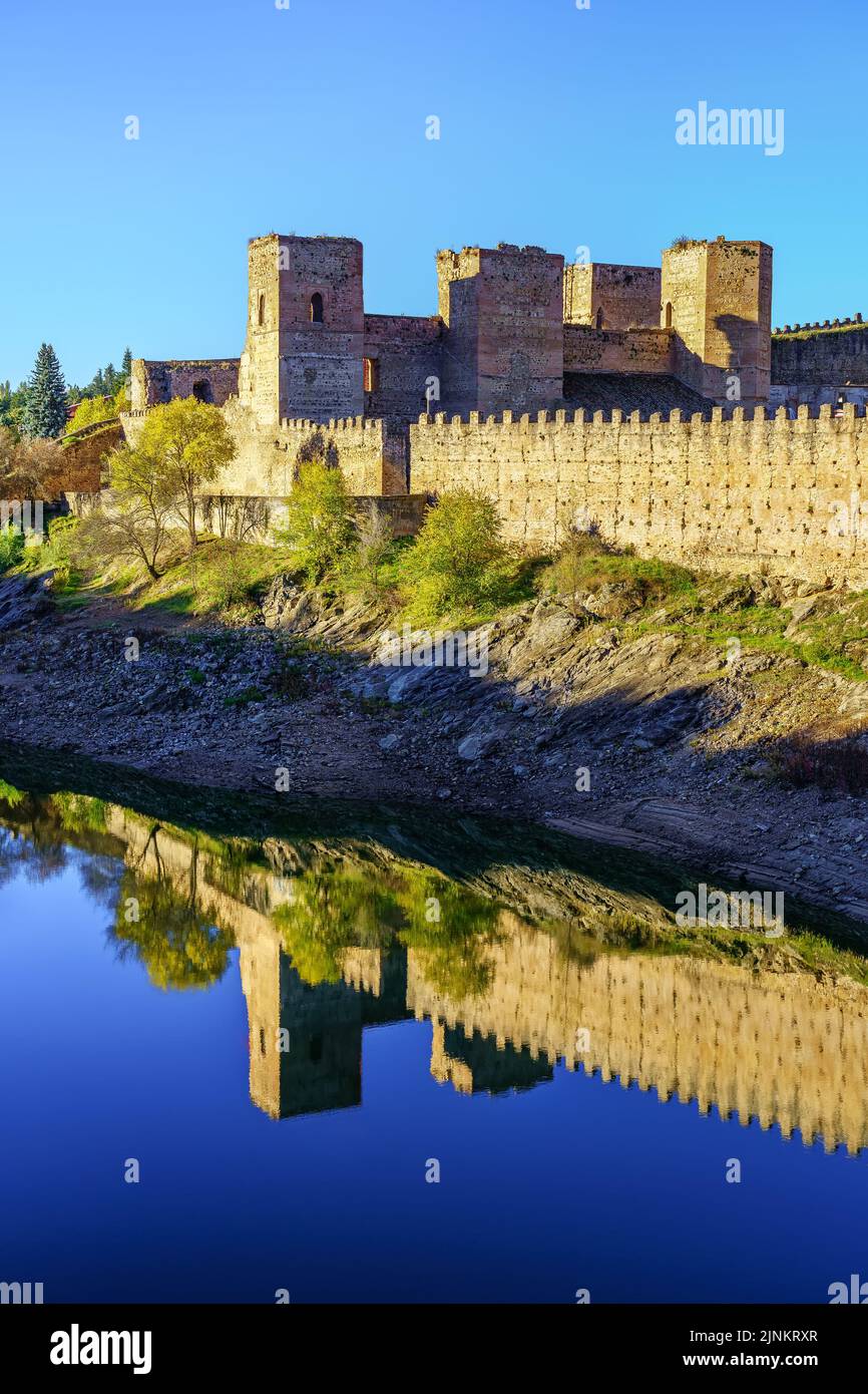 Medieval castle and wall with its reflection in the river that passes ...