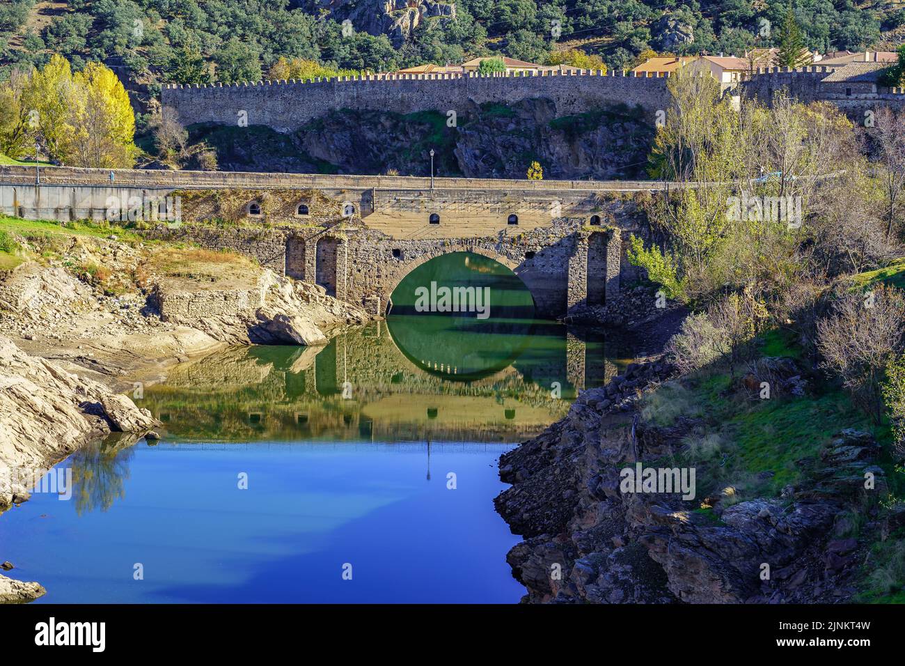 Old stone bridge over the river next to the city of Buitrago de Lozoya ...