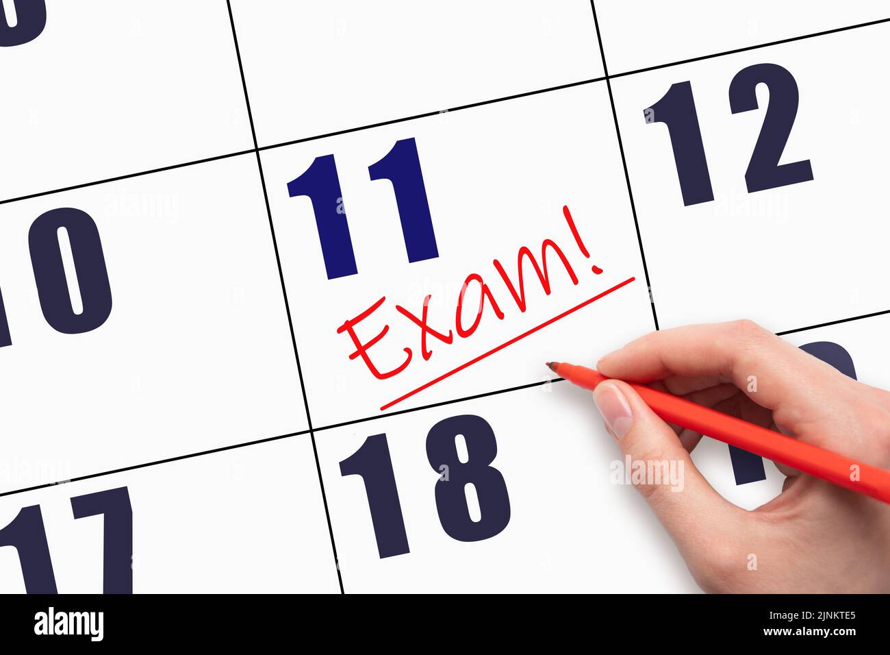 11th day of the month. Hand writing text EXAM and drawing a line on ...