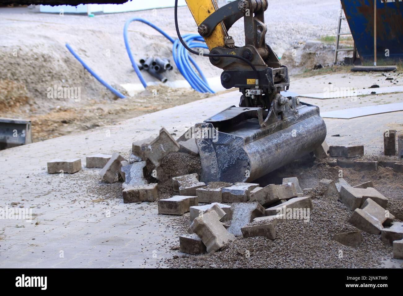 Excavator removes concrete paving from a yard area Stock Photo - Alamy