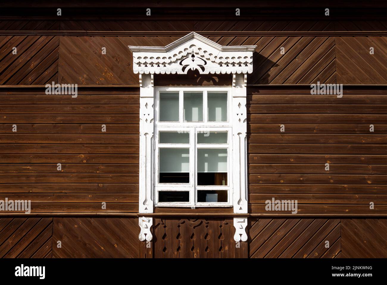 carved window in Russian old style with white architraves, on wooden ...
