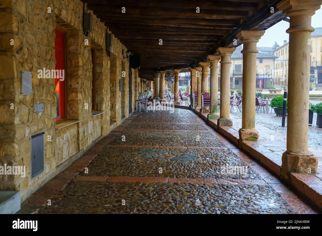 Arches with ancient stone columns in the main square of a medieval town ...