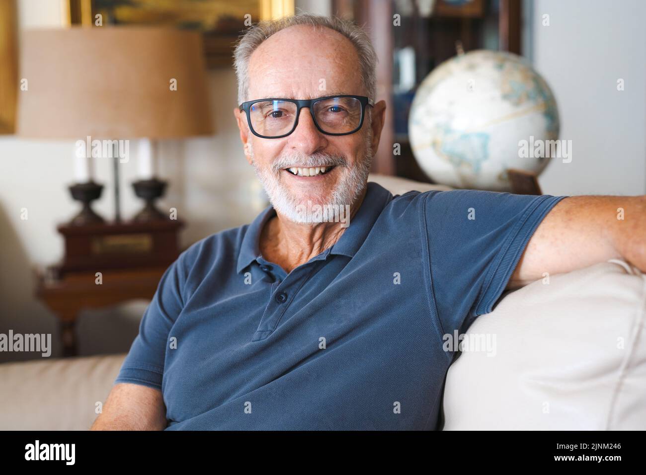 Head shot portrait close up smiling older retired man sitting on couch ...