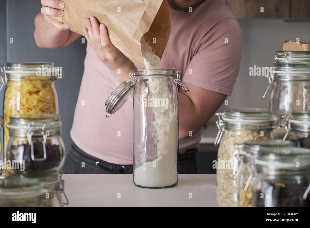 Unrecognizable latin man filling up a jar with wheat flour from a paper ...