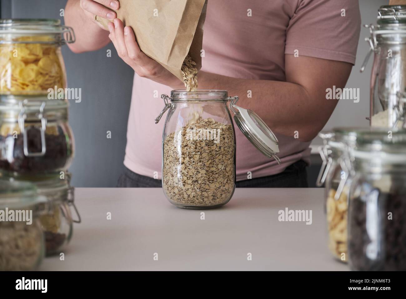 Unrecognizable latin man filling up a jar with oat flakes from a paper ...